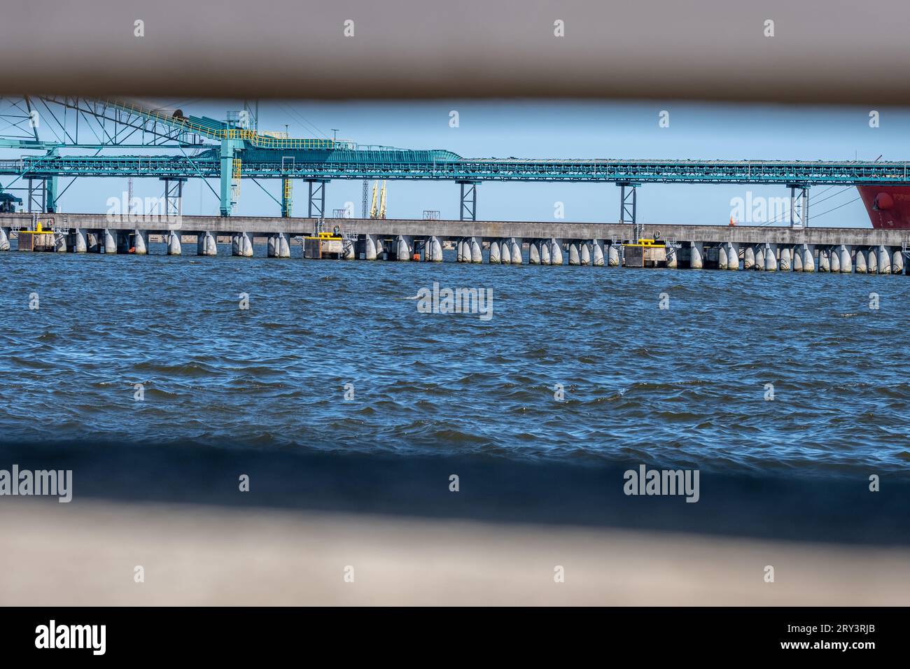 Cargo ship wharf in port, coal terminal on opposite bank of the river ...