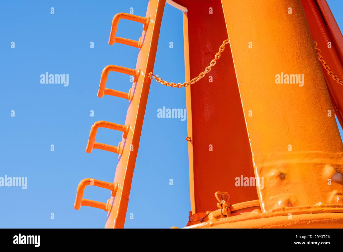 A huge metal bright orange tube on the seashore. In the background, a ...