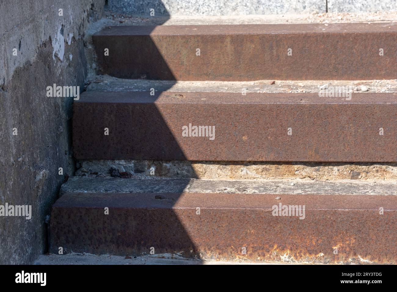 Metal and concrete old rusty steps with shadow next to concrete wall ...