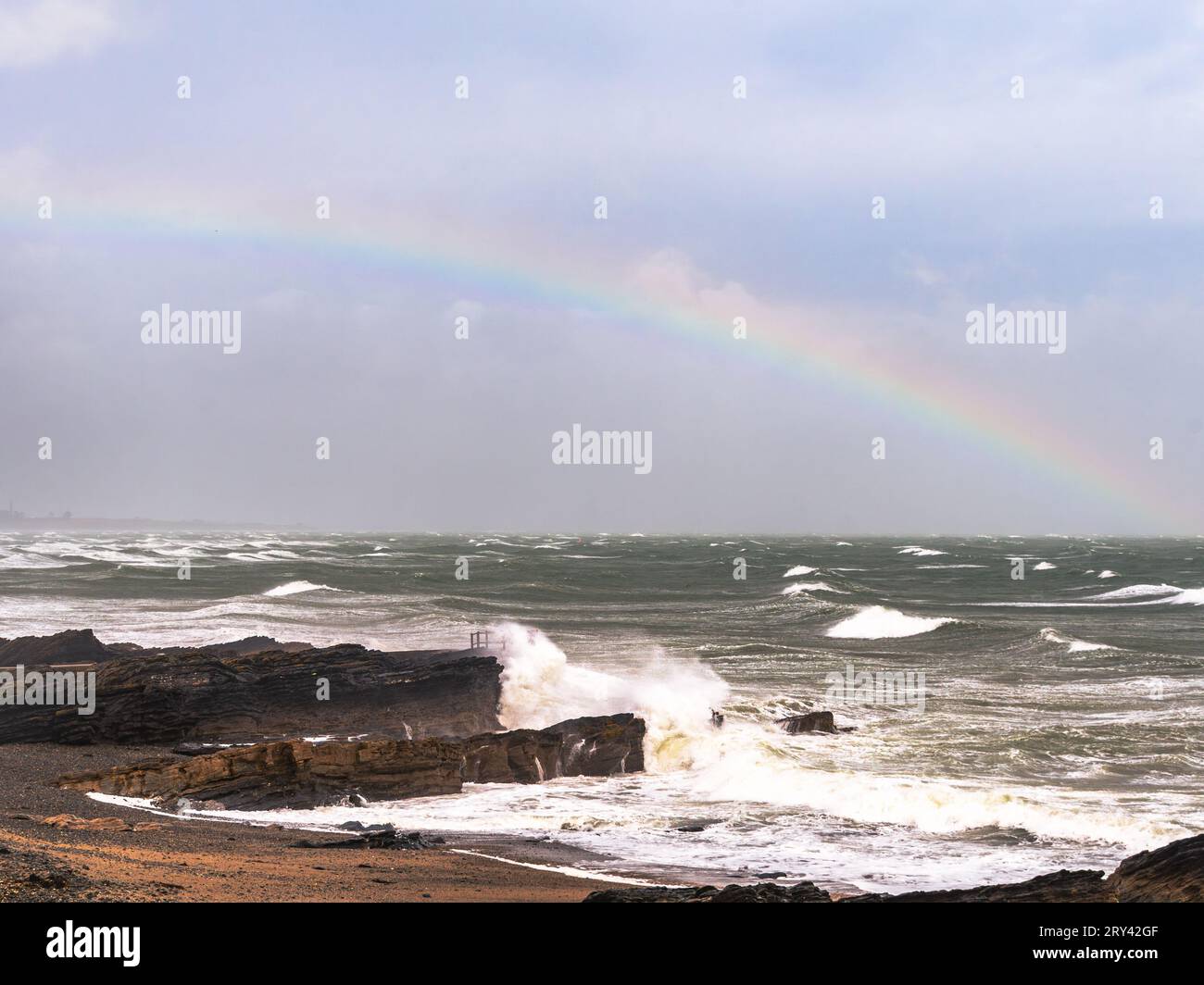 Faint rainbow over a windy High Rock during Storm Agnes Stock Photo - Alamy