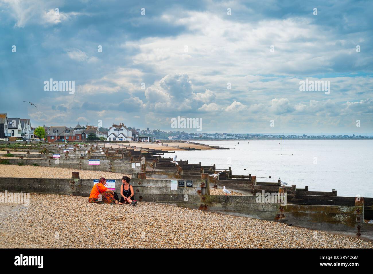 Whitstable, UK - Sep 12 2023 Two ladies sit on the quiet beach with ...