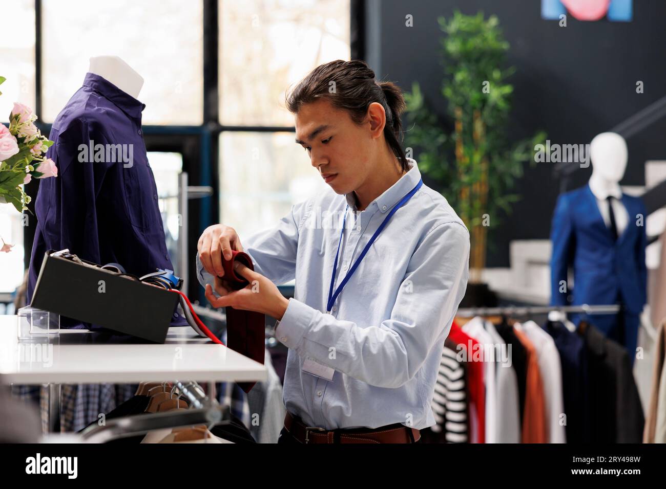 Asian customer arranging stylish accessories in modern boutique ...