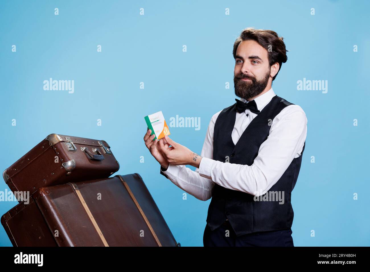 Hotel porter holding vitamins in studio, posing with box of medicaments ...