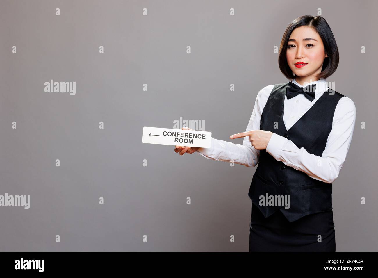 Asian woman receptionist holding conference room directional tabletop ...