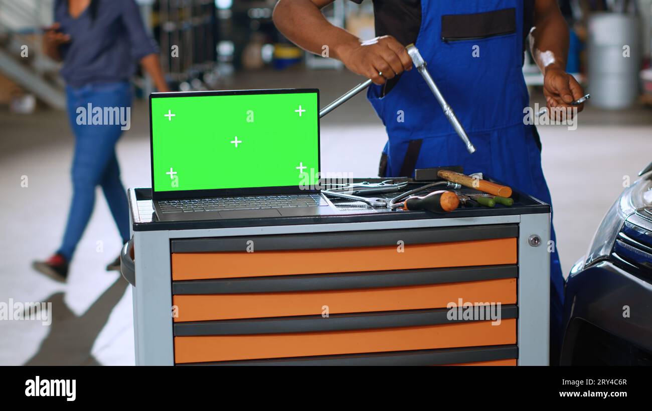 Green screen laptop placed on working bench in busy garage next to ...