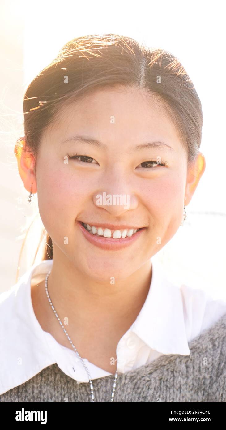 Vertical Portrait of an friendly asian student girl laughing and ...