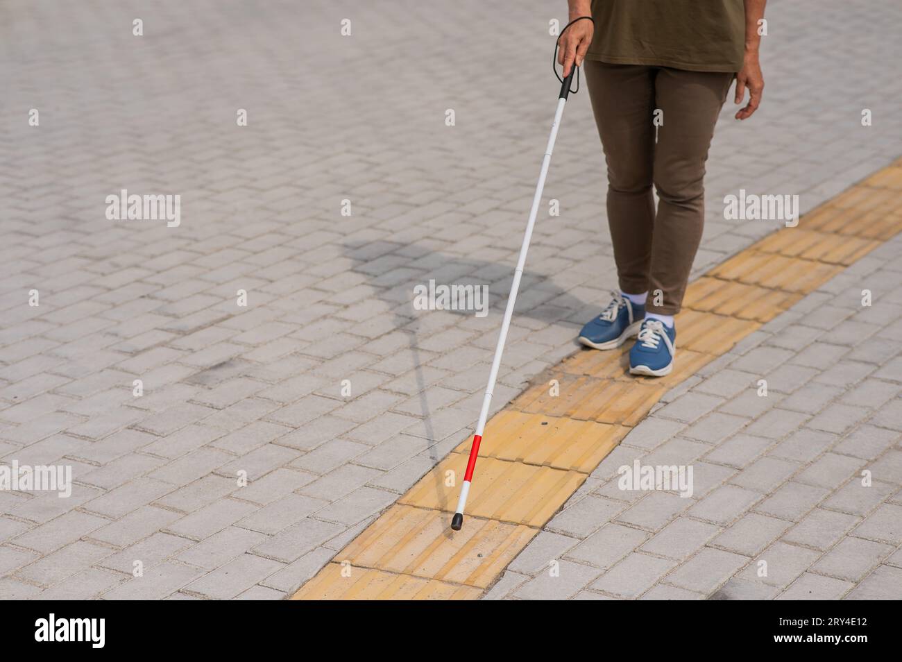 Close-up of the legs of an elderly blind woman with a cane at a tactile ...