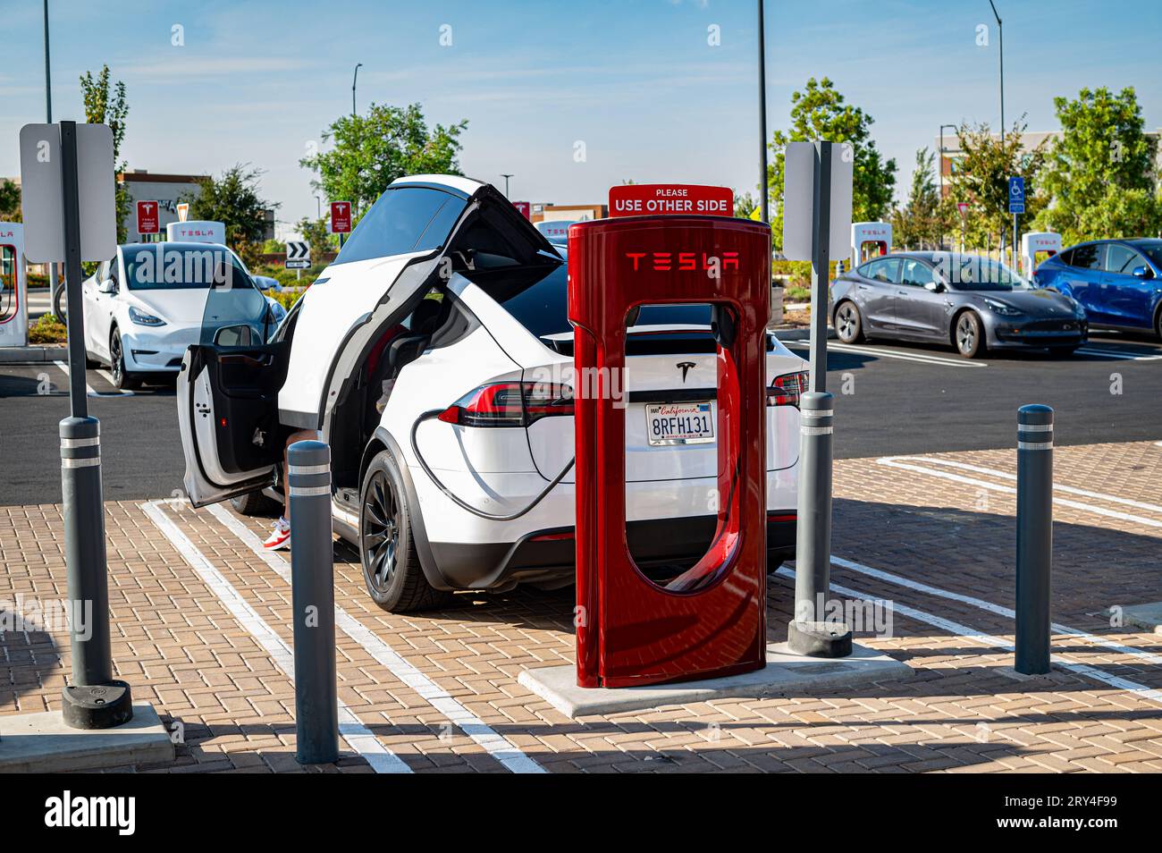 A Model X Tesla with falcon doors charges at the special crimson ...