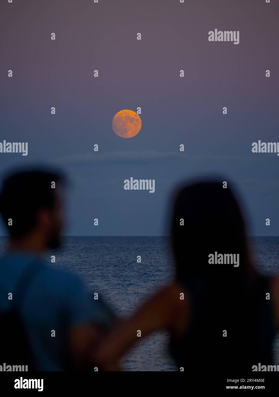 Barcelona/Spain The full moon appears over the city of Barcelona, Spain ...