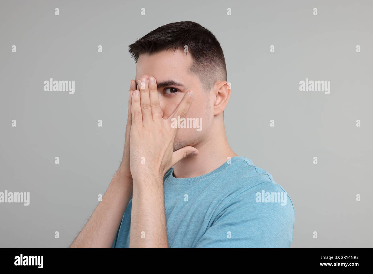 Embarrassed man covering face with hands on grey background Stock Photo ...
