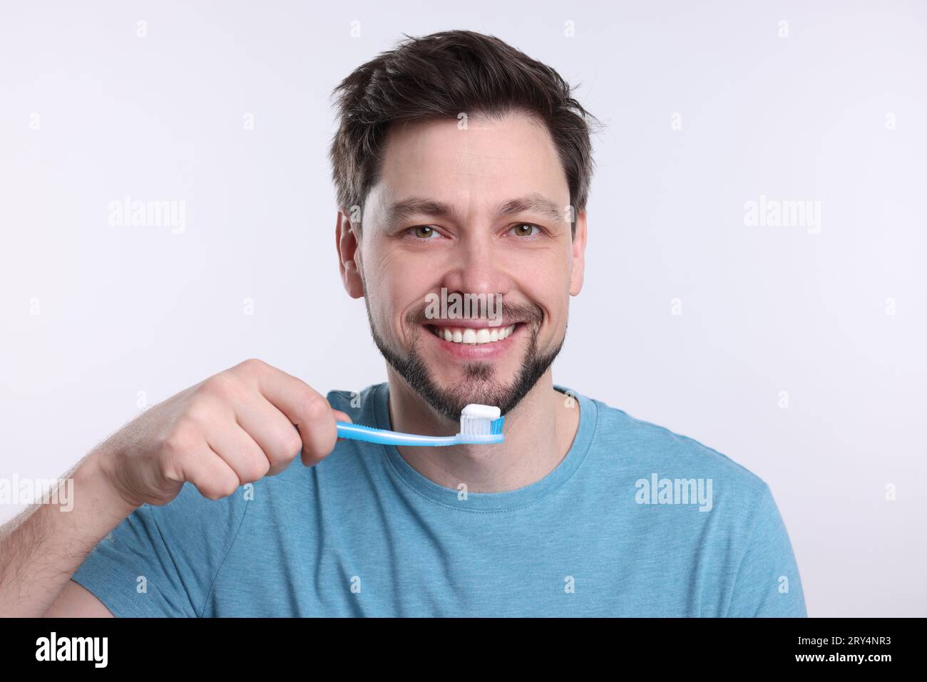 Happy man holding plastic toothbrush on white background. Mouth hygiene ...