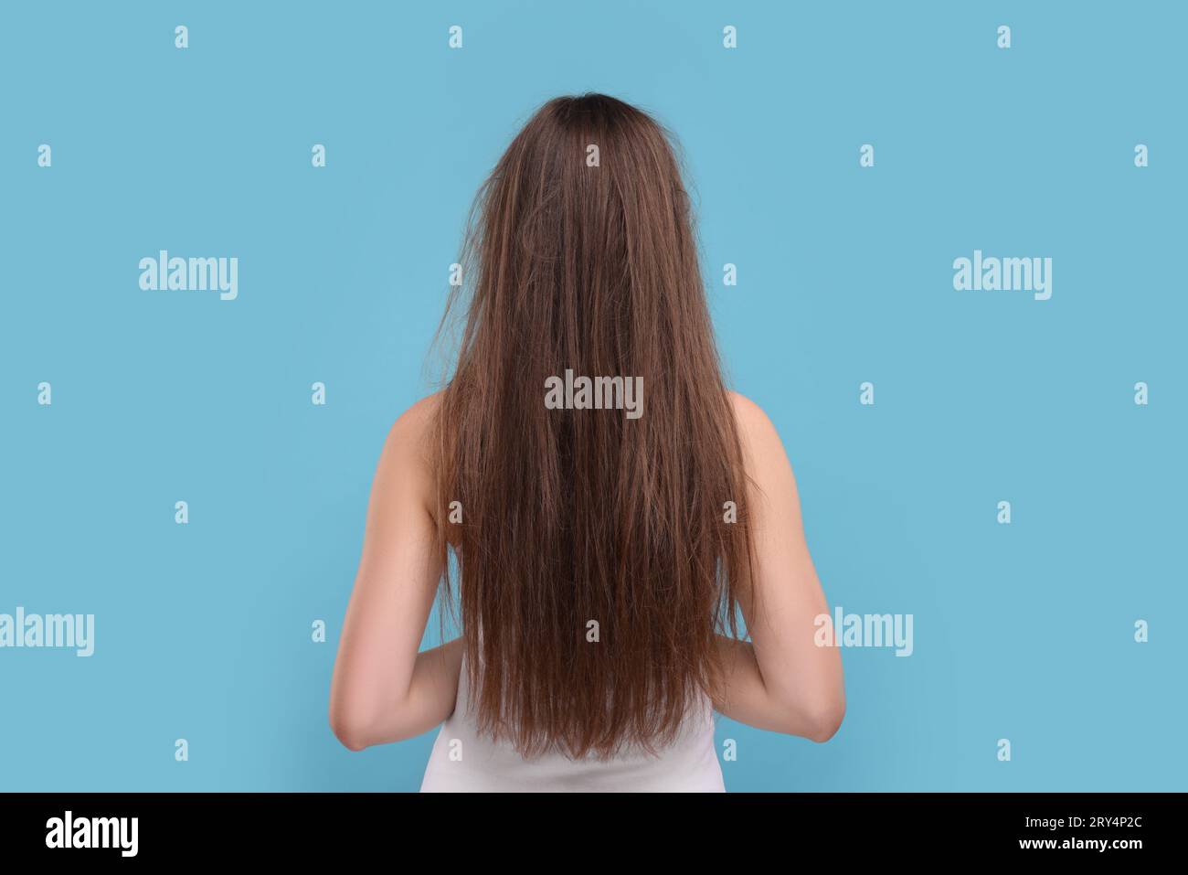 Woman with damaged messy hair on light blue background, back view Stock ...