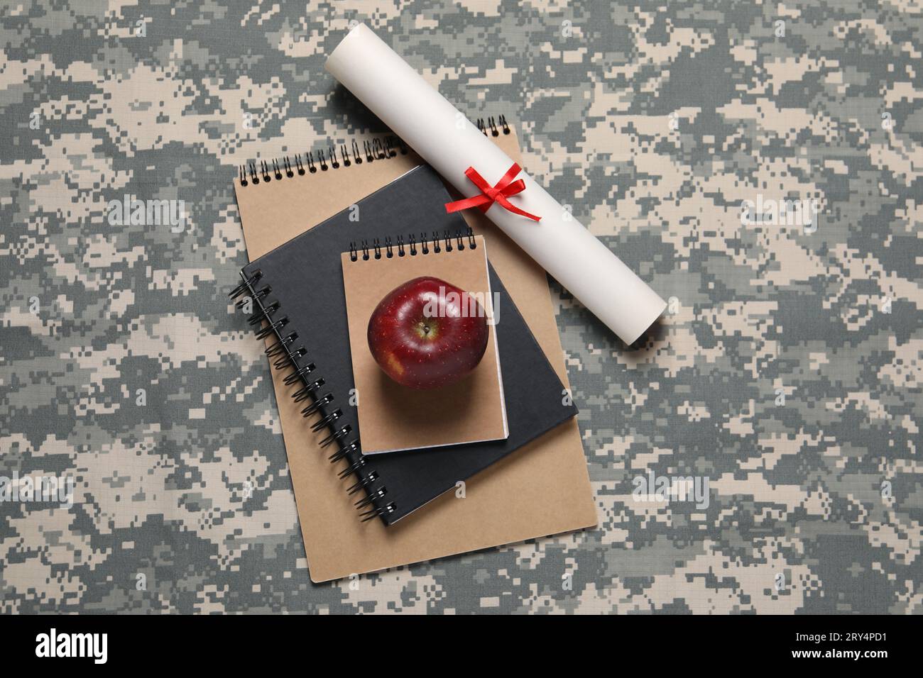 Notebooks, apple and diploma on camouflage background, flat lay ...