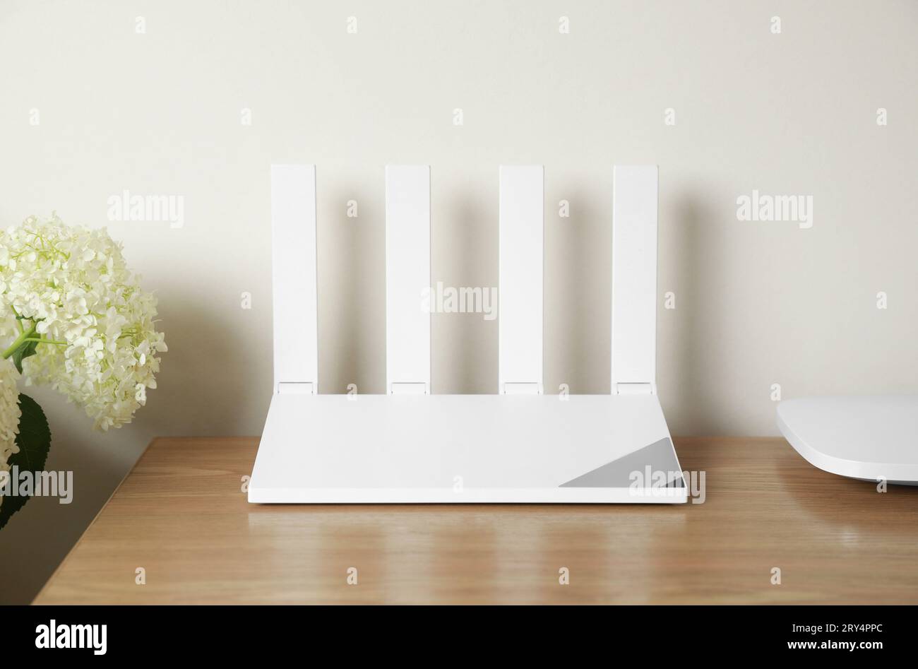 New modern Wi-Fi router on wooden table near white wall Stock Photo - Alamy