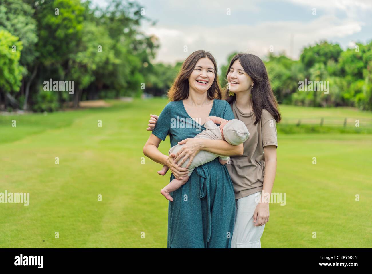 A happy 40-year-old mother cradles her newborn with her adult daughter ...