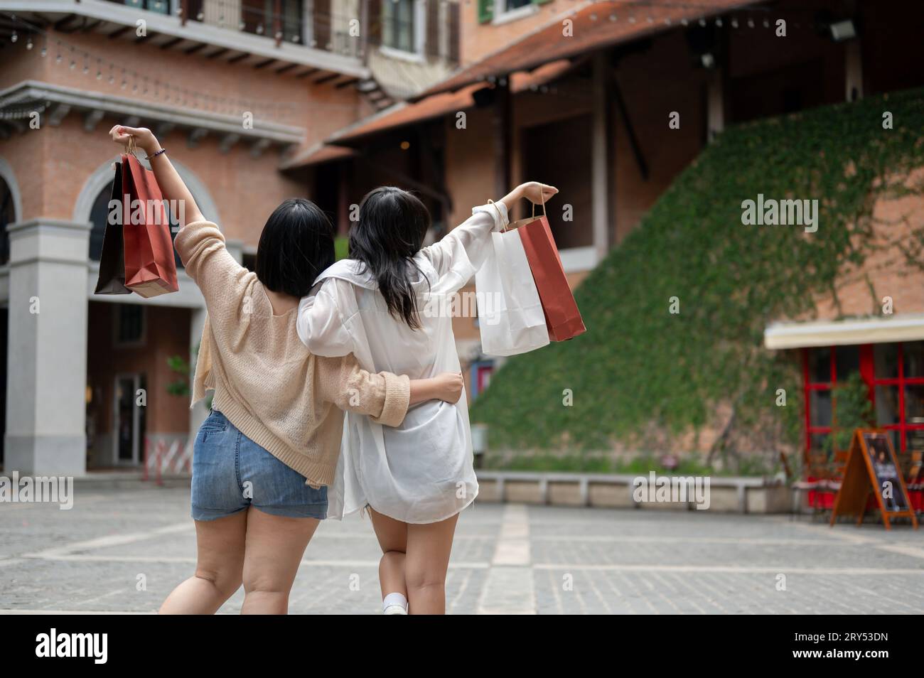 Back view image of two happy Asian female friends are holding their ...