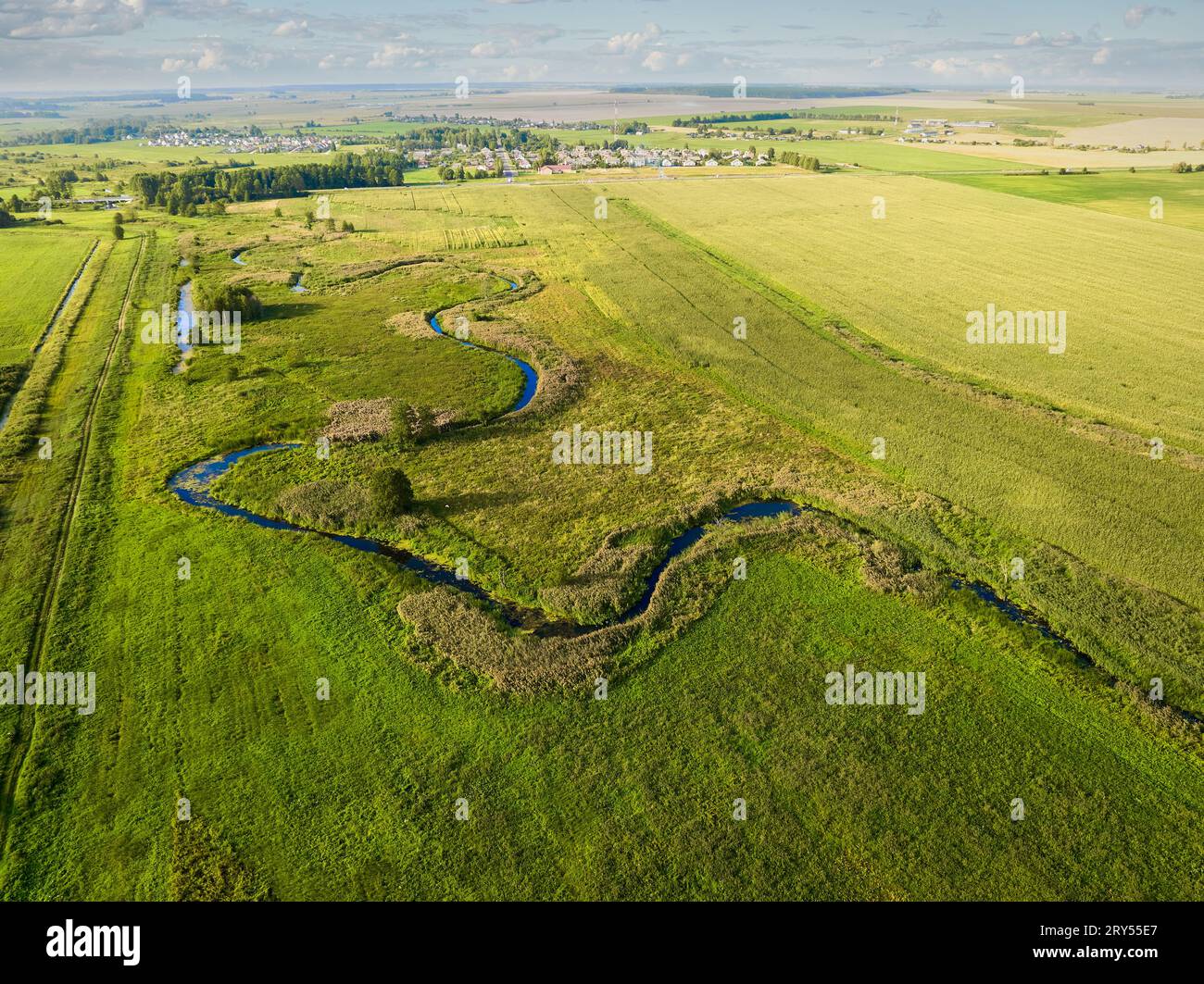 Small river flows among fields illuminated by sunset light Stock Photo ...