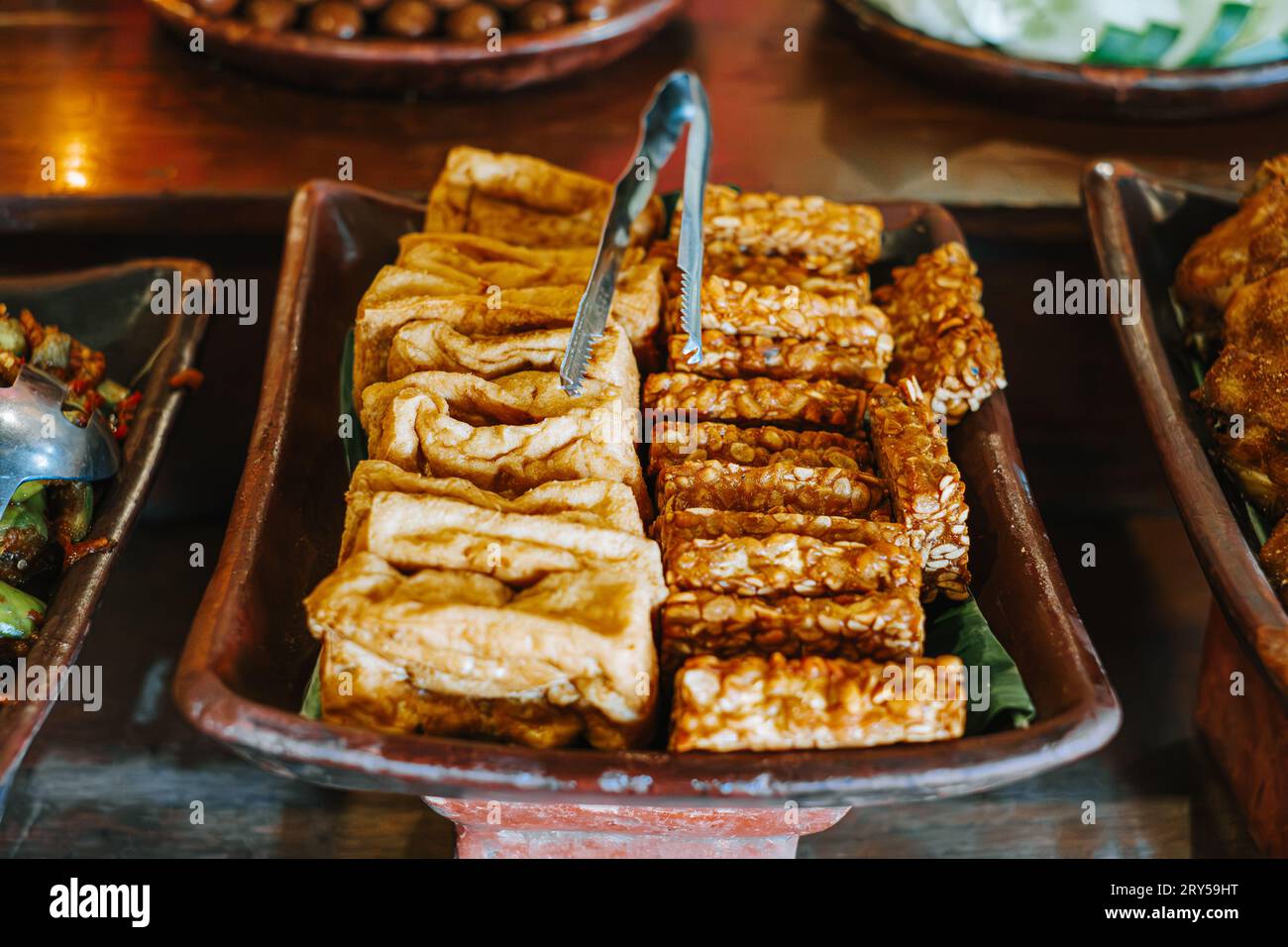 Fried tempe and tahu on clay plate. Traditional Indonesian condiment ...