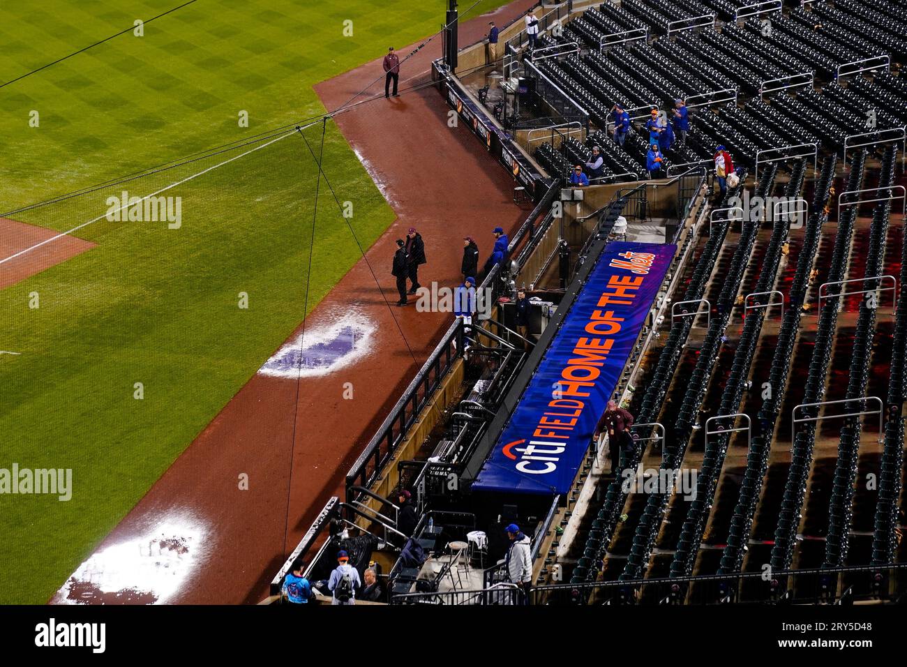 Fans watch as grounds crew members work on the field during a rain ...