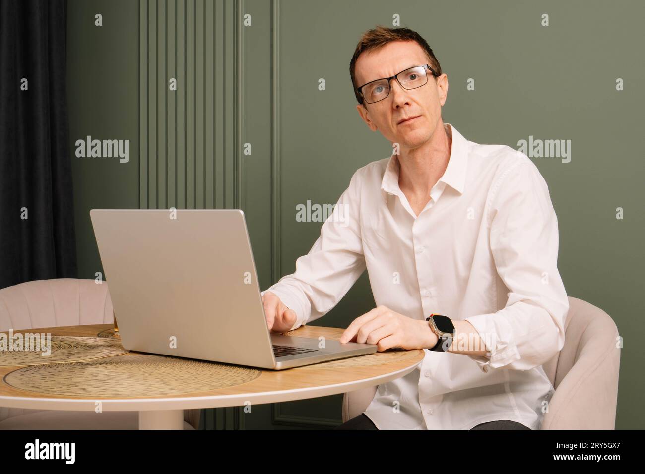 Portrait of middle aged , thin business man sitting at round table on ...