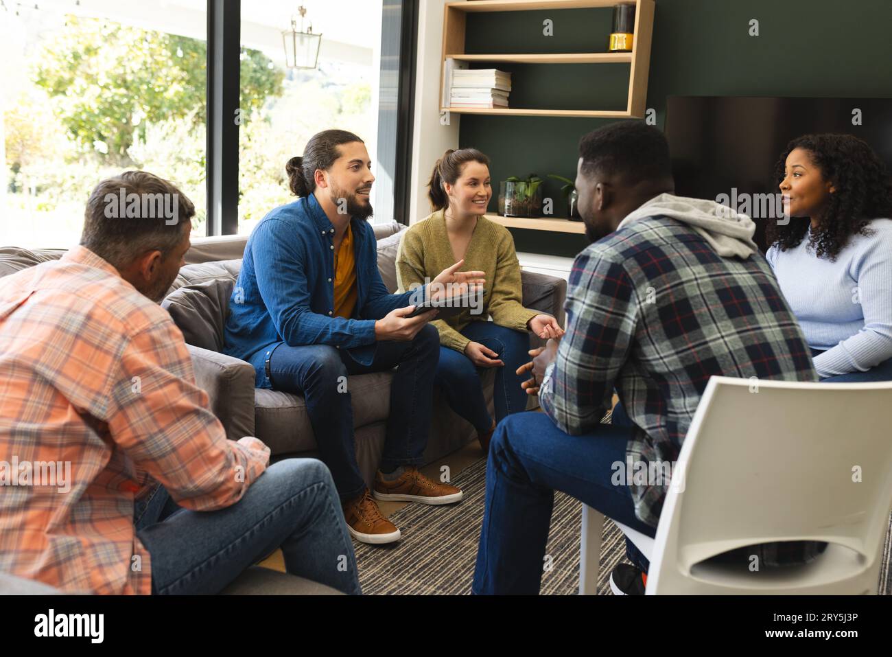 Diverse group of friends and male therapist with tablet in group ...