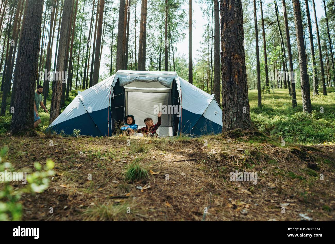 cute caucasian boys sitting inside a big touristic tent. Family camping ...