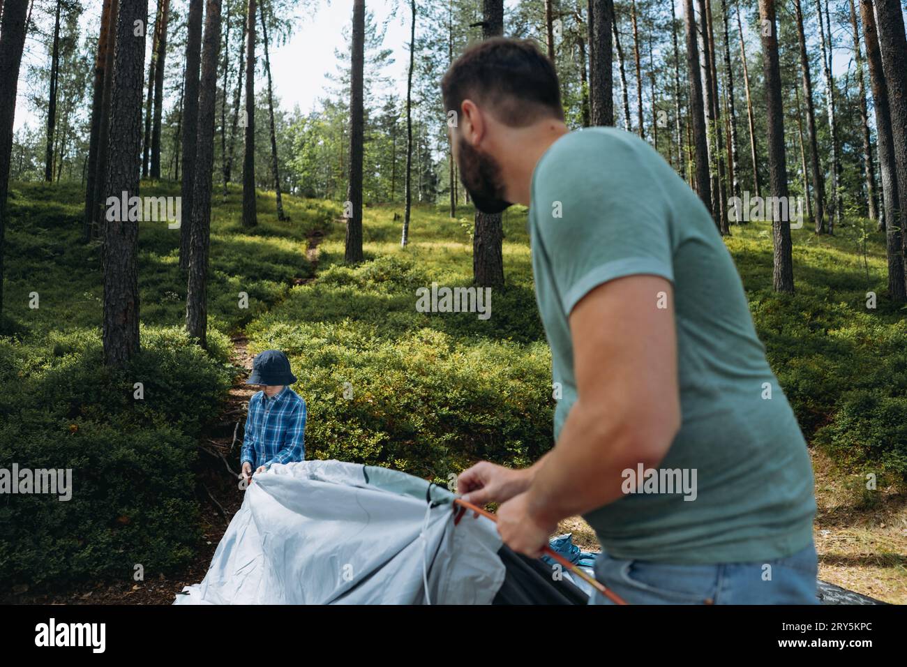 cute caucasian boy helping father to put up a tent. Family camping concept Stock Photo - Alamy