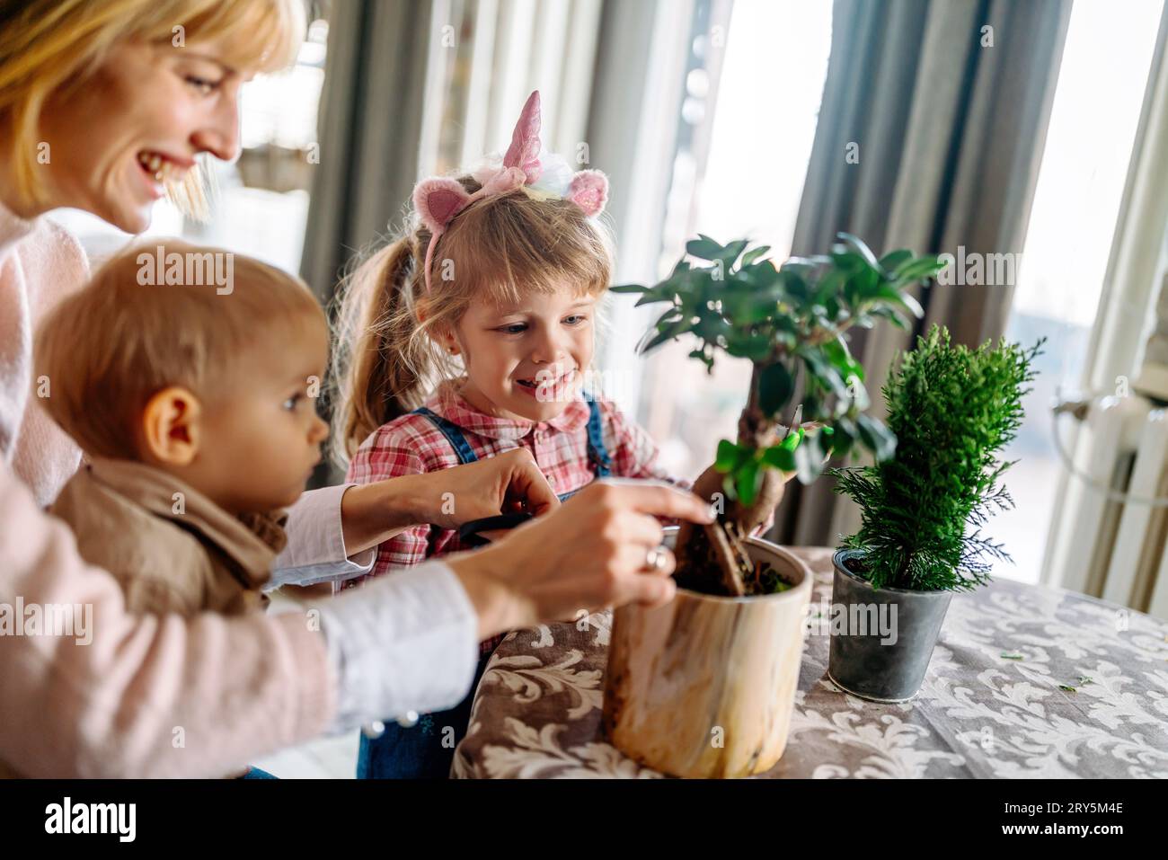 Young woman with her children taking care of plants indoors. Family ...
