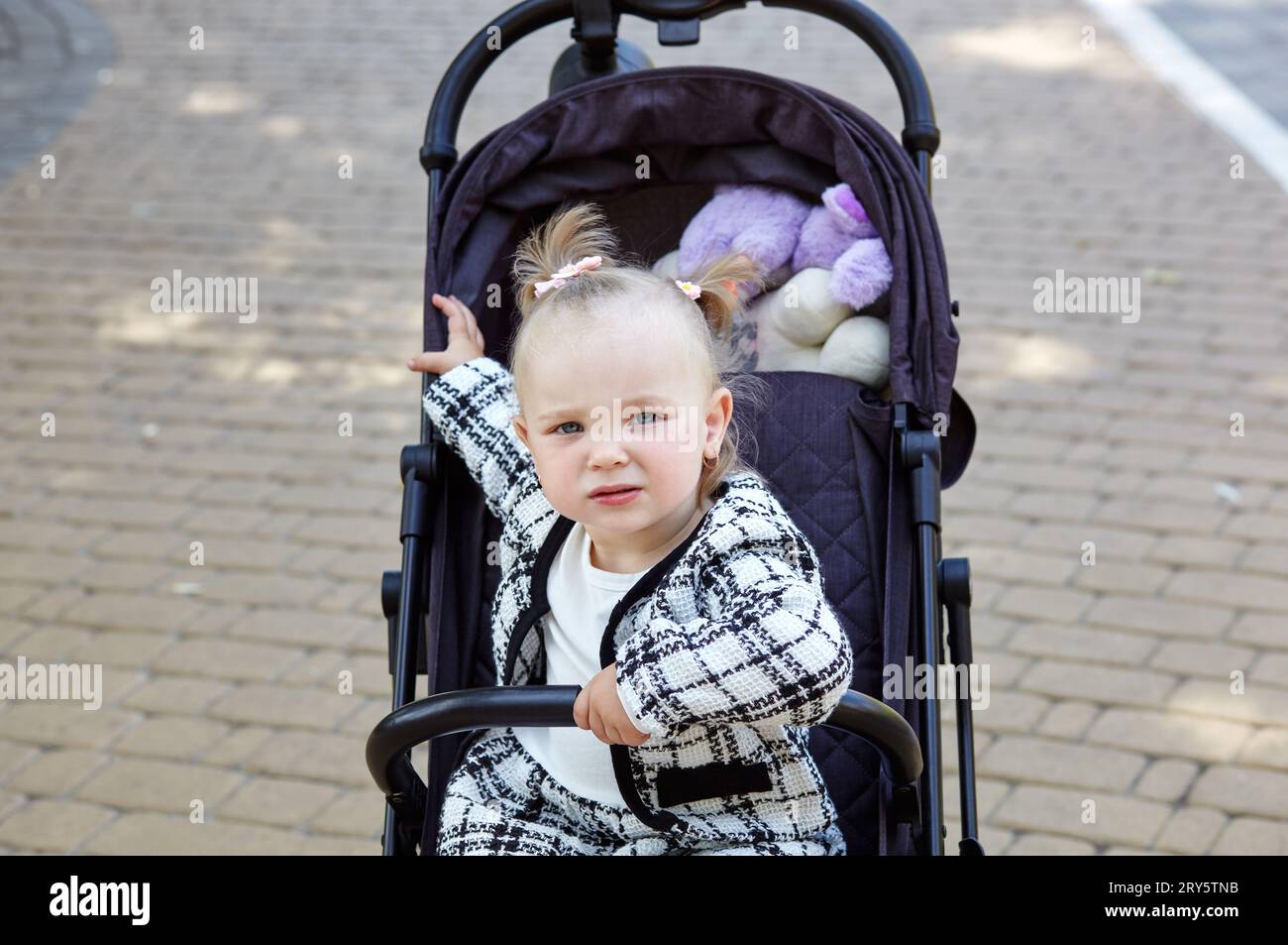 Baby in stroller on a walk in summer park. Adorable little girl sitting ...