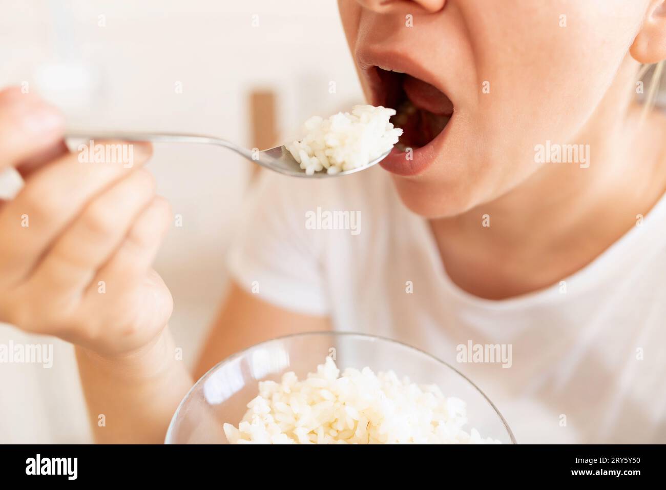 a woman stuffs a spoonful of rice into her mouth. concept of proper ...