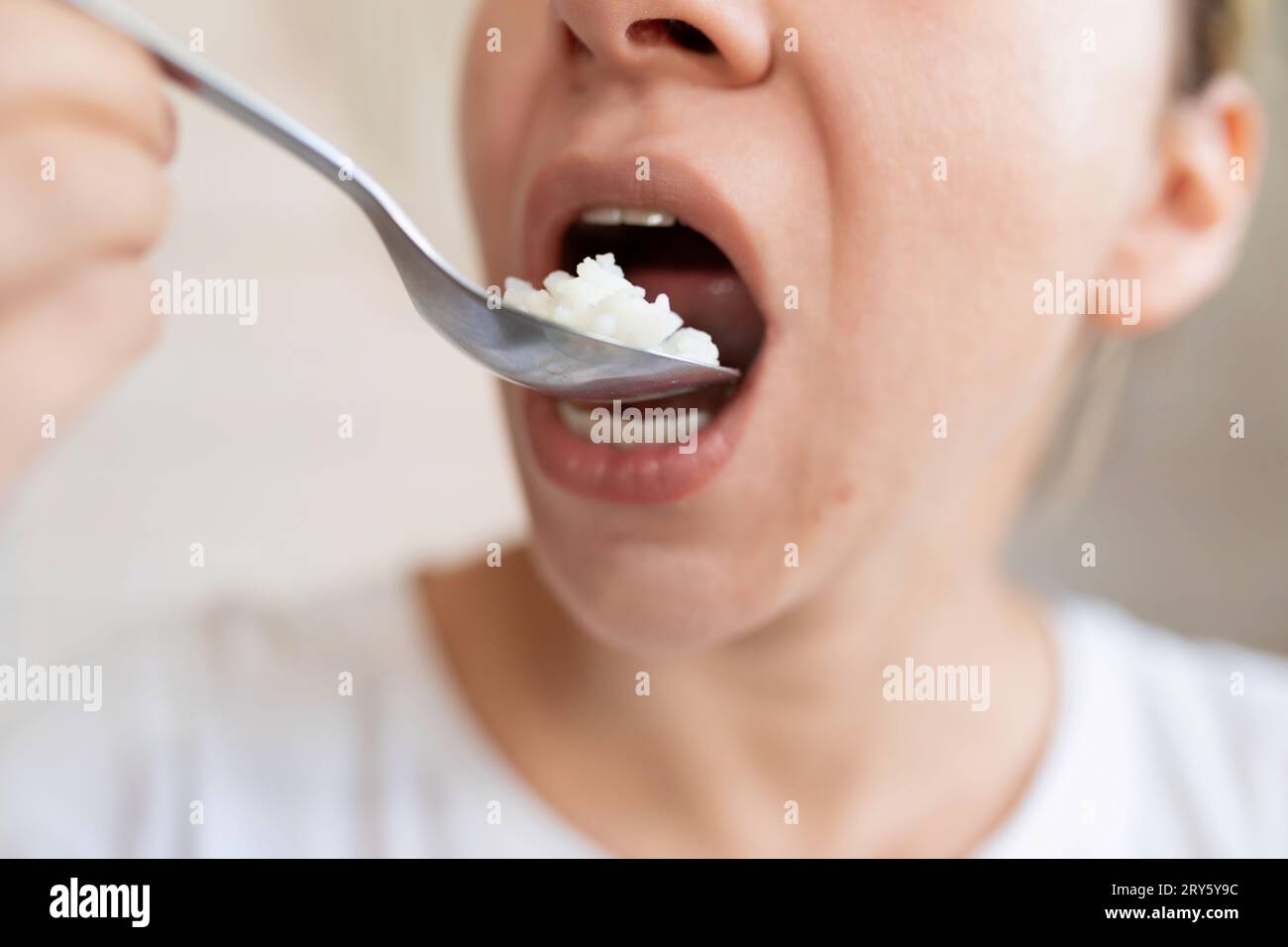 a woman stuffs a spoonful of rice into her mouth. concept of proper ...