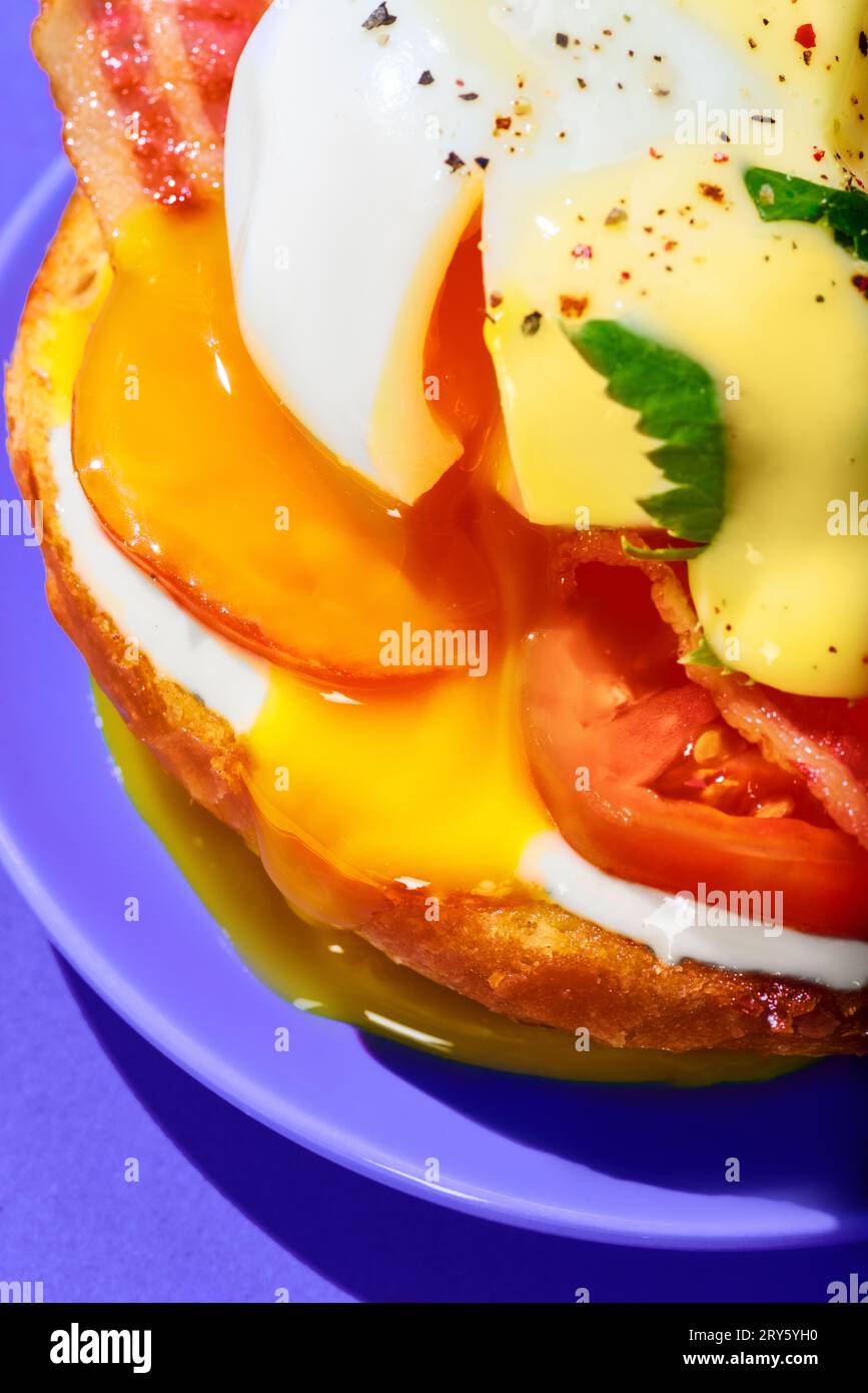 Close-up of poached eggs with liquid yolk, tomato, bacon and cheese ...