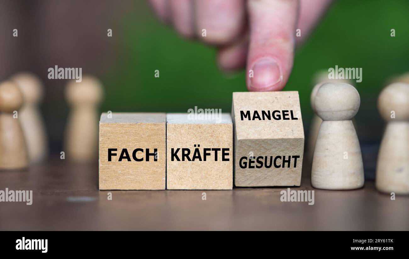 Hand turns wooden cube and changes the German expression 'Fachkraefte ...