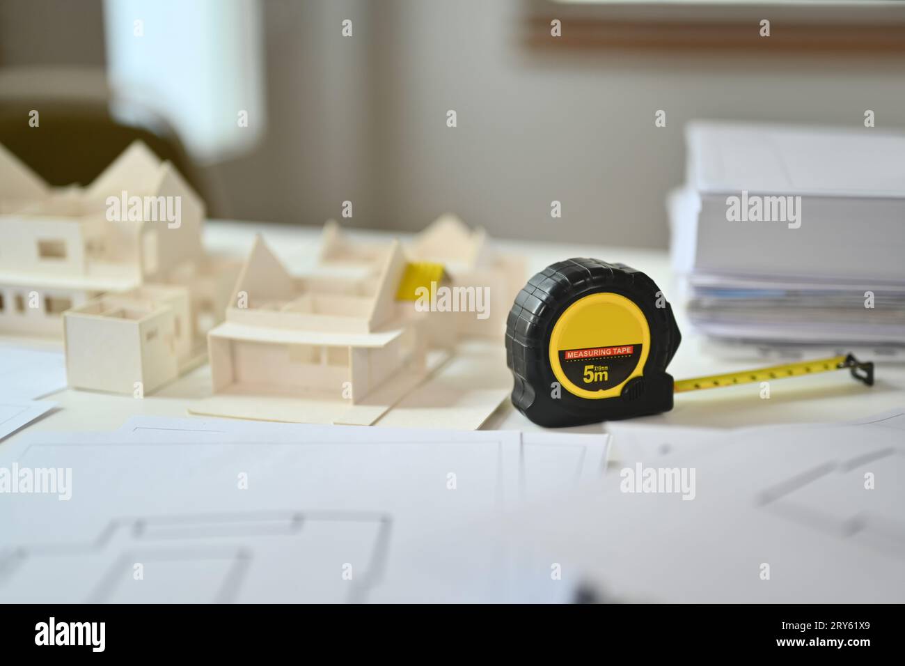 A measuring tape, architectural model and blueprints on desk. Building ...