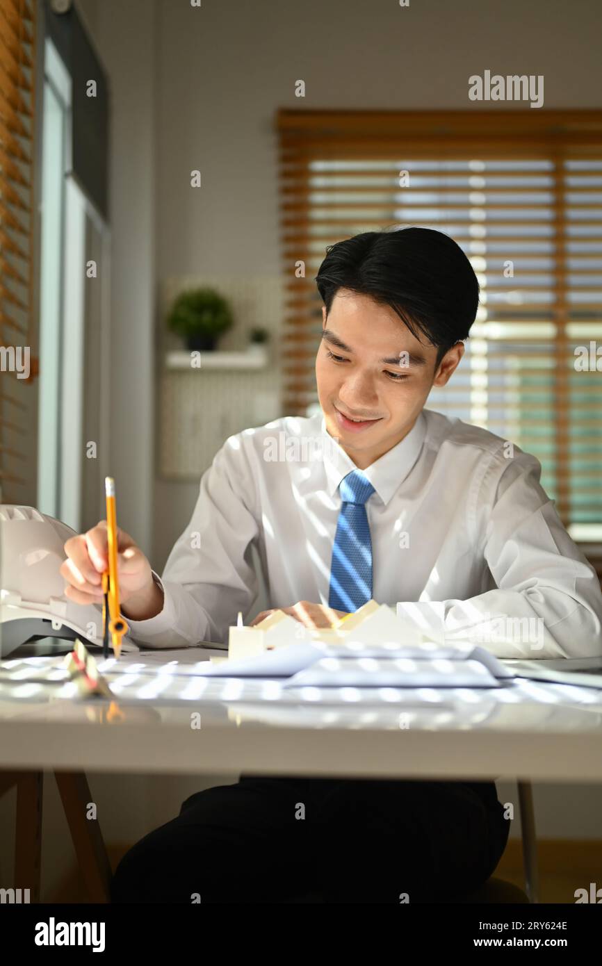 Smiling architect man hand compass to measuring scale on a blueprint ...
