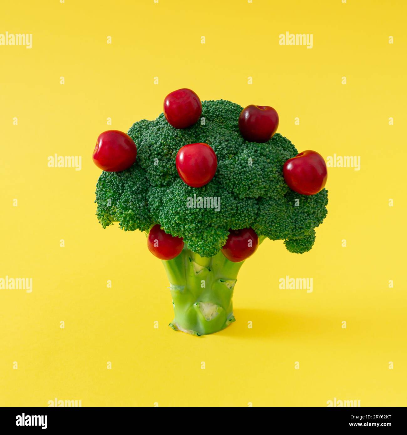Fruit tree made of green broccoli and red cherries on light pastel ...