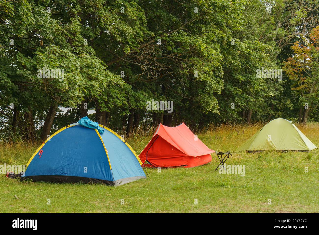Three stable camping tents of various colours, blue, red and light ...