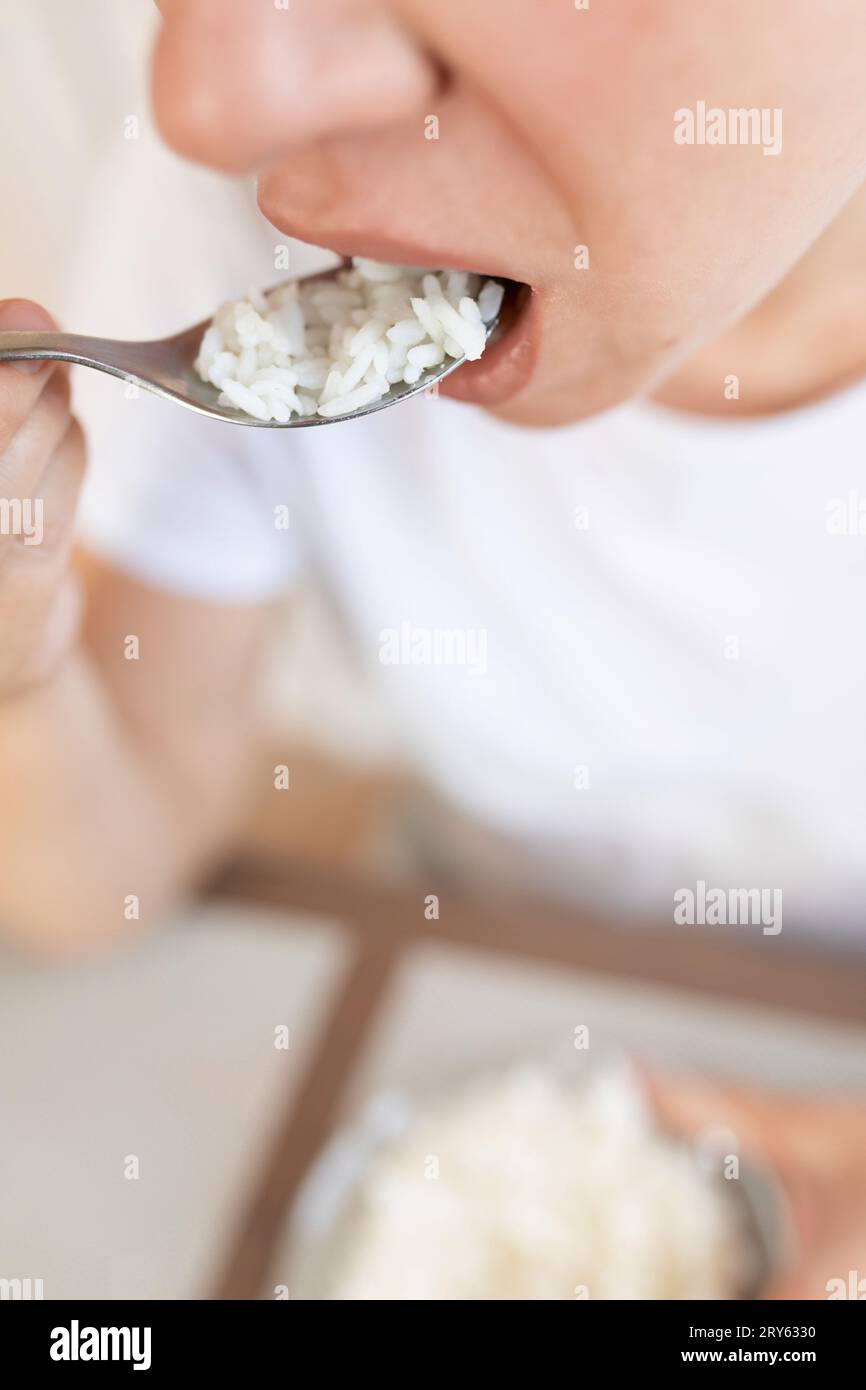 young woman brings a spoon of rice to her mouth Stock Photo - Alamy