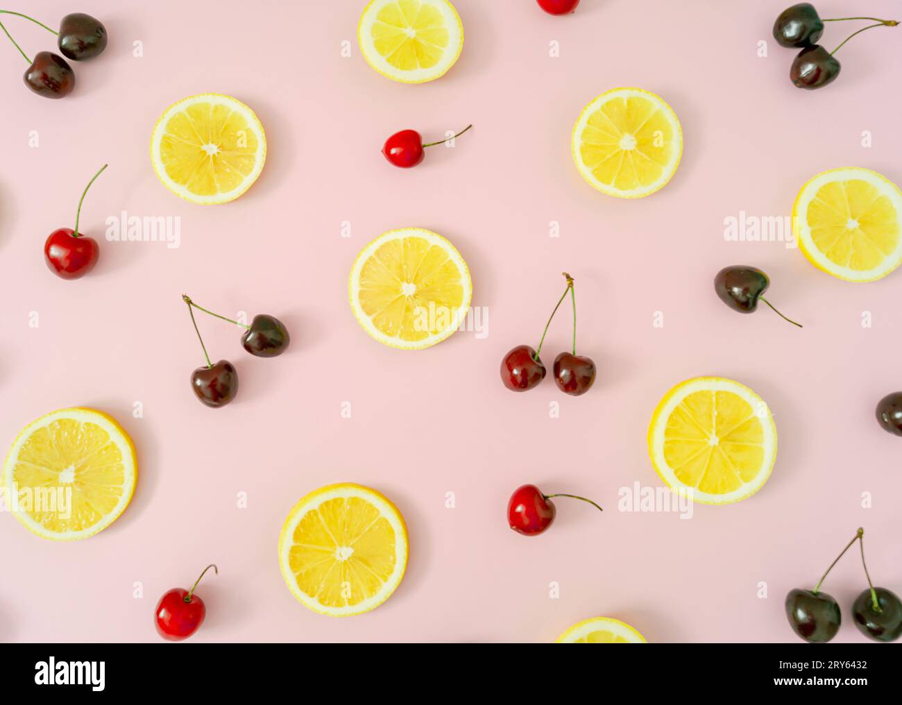 Creative fruit pattern made of red cherries and yellow lemon slices on ...
