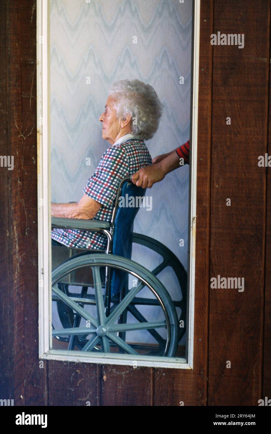 Elderly woman being pushed in a wheelchair in her home in California ...