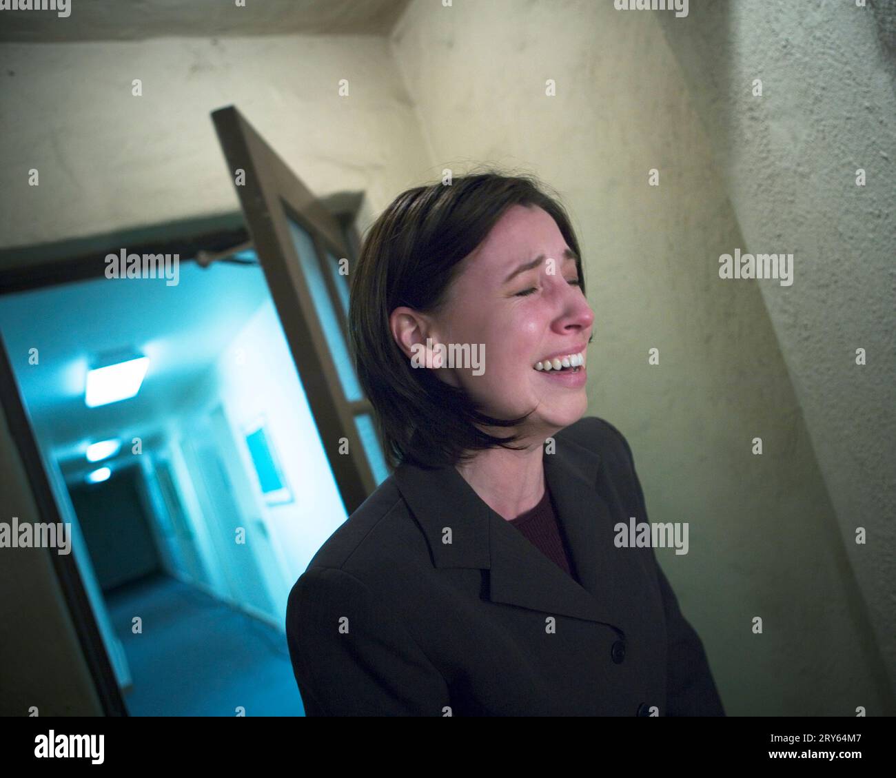 A crying young woman standing outside a buildings entrance at night ...