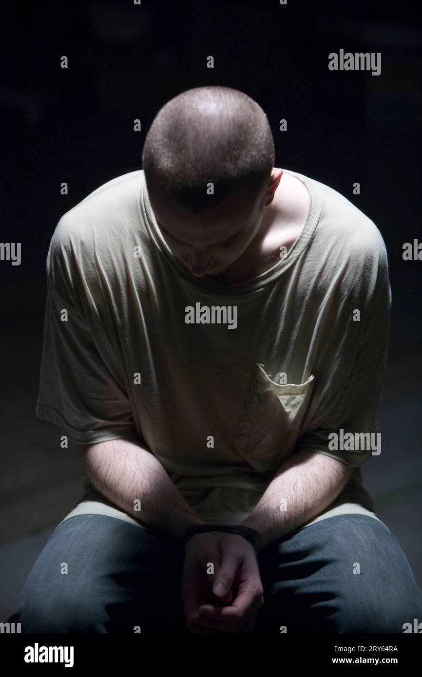 Front view of a seated man with his hands taped together in his lap ...