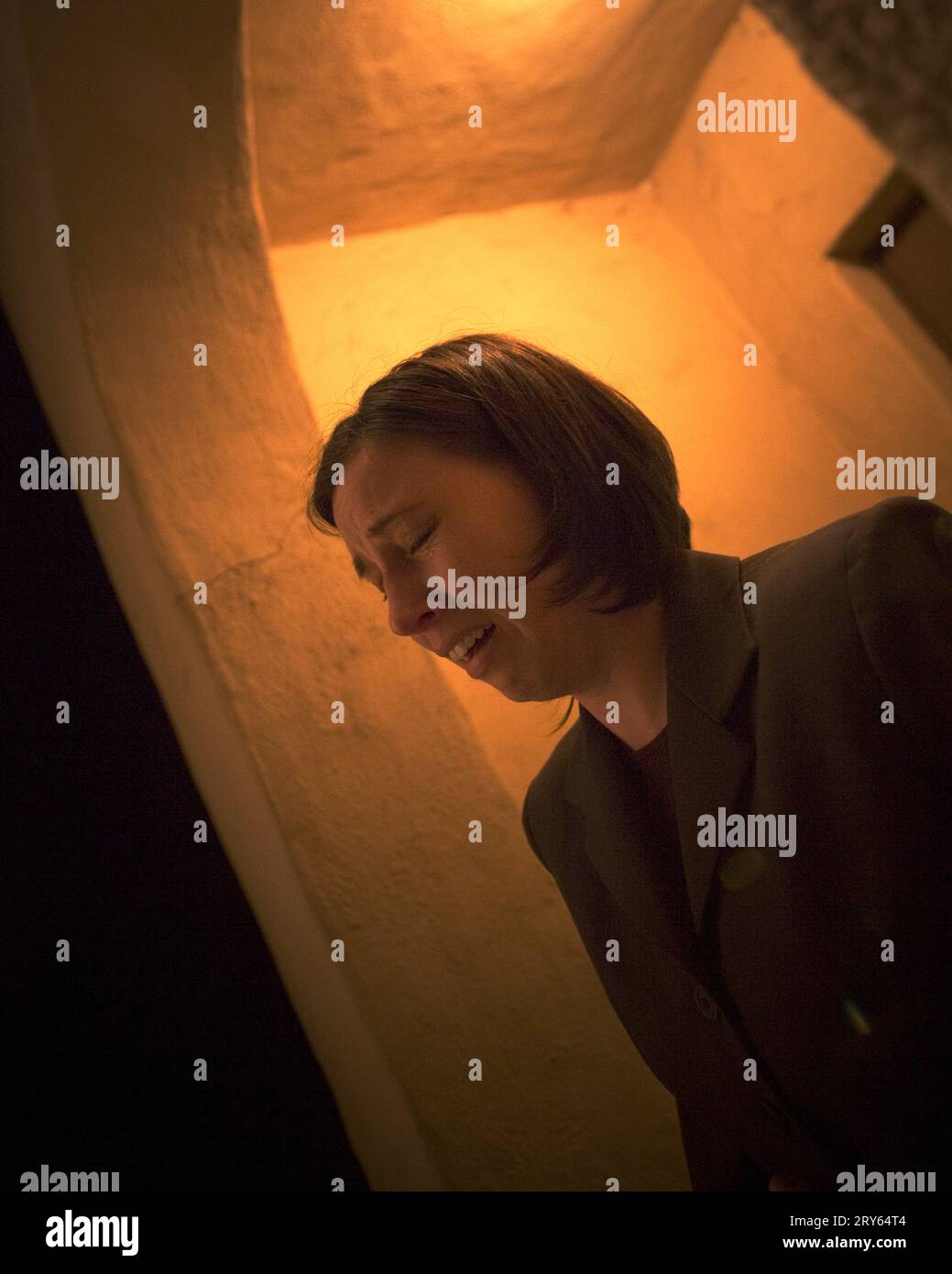 A crying young woman standing outside a buildings entrance at night ...