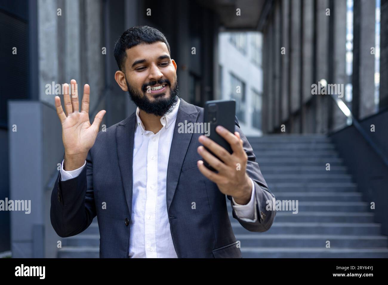 Smiling young Muslim male businessman praying near office building ...