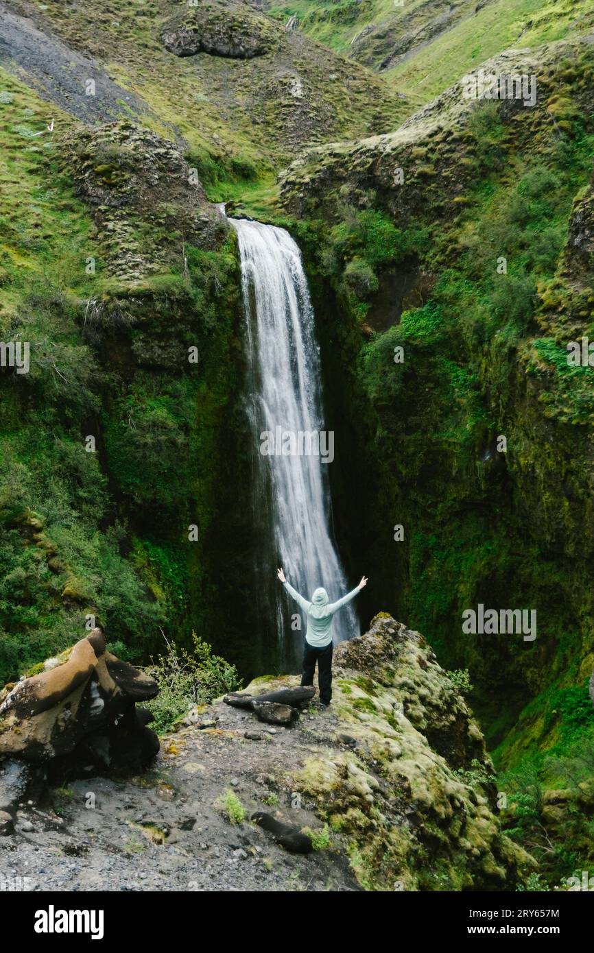 Woman hikes to waterfall overlook with green lush mountains Stock Photo ...