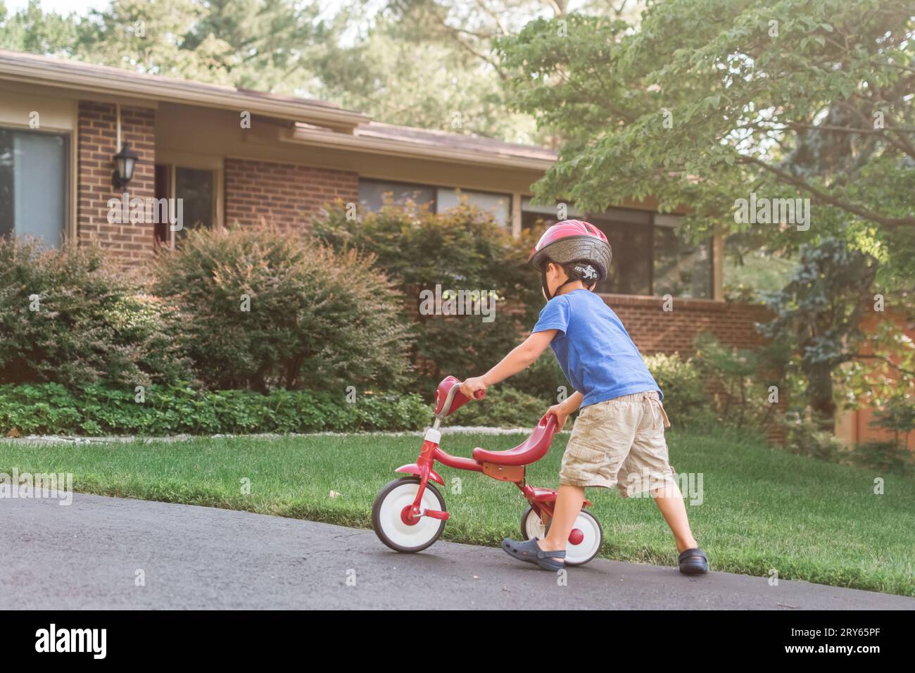 Young boy riding tricycle on suburban driveway Stock Photo - Alamy
