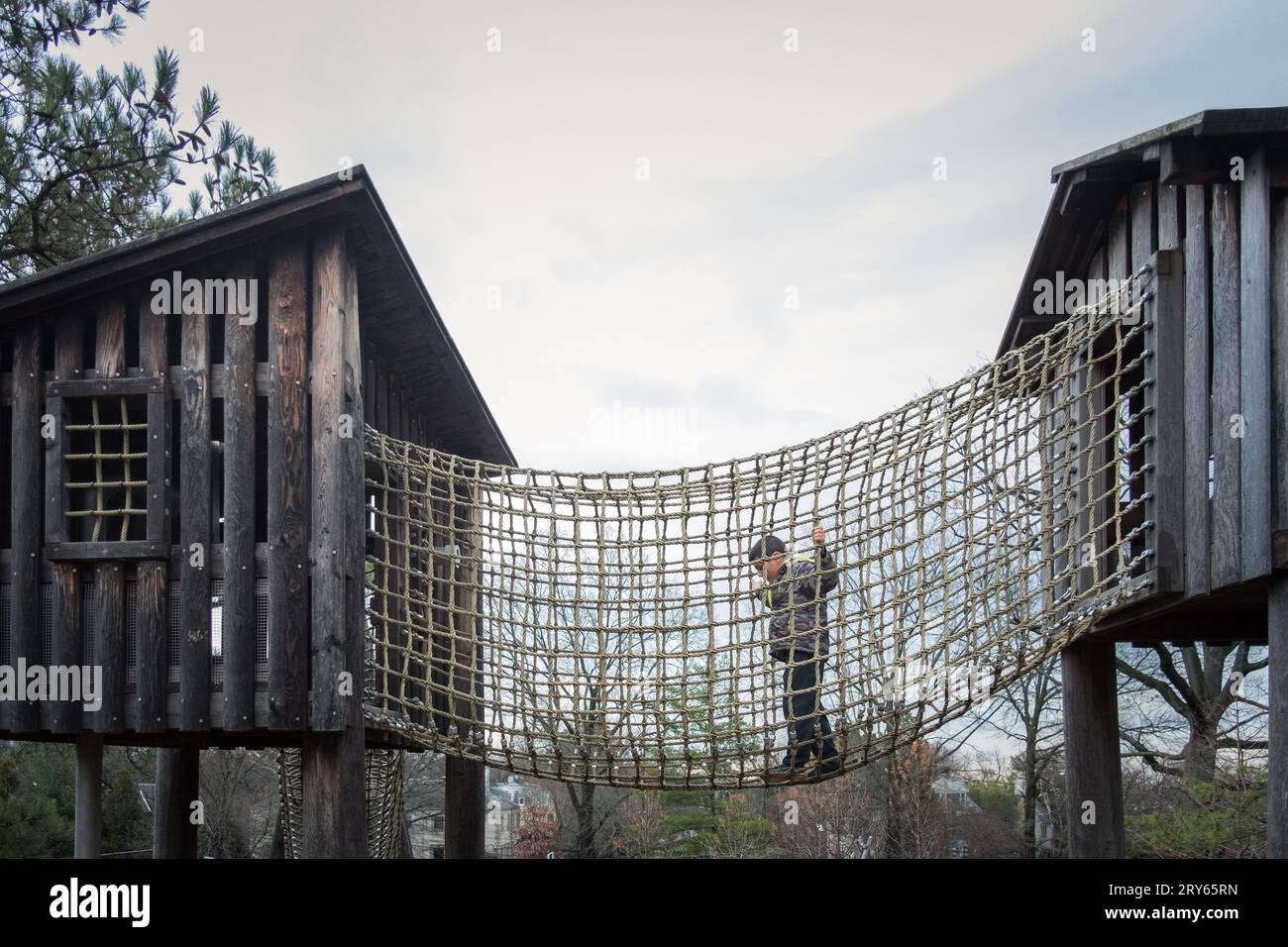 Young boy crossing rope bridge at suburban playground Stock Photo - Alamy