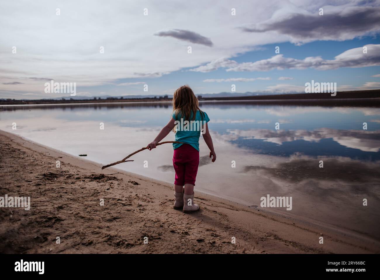 Young girl throwing stick into lake Stock Photo - Alamy