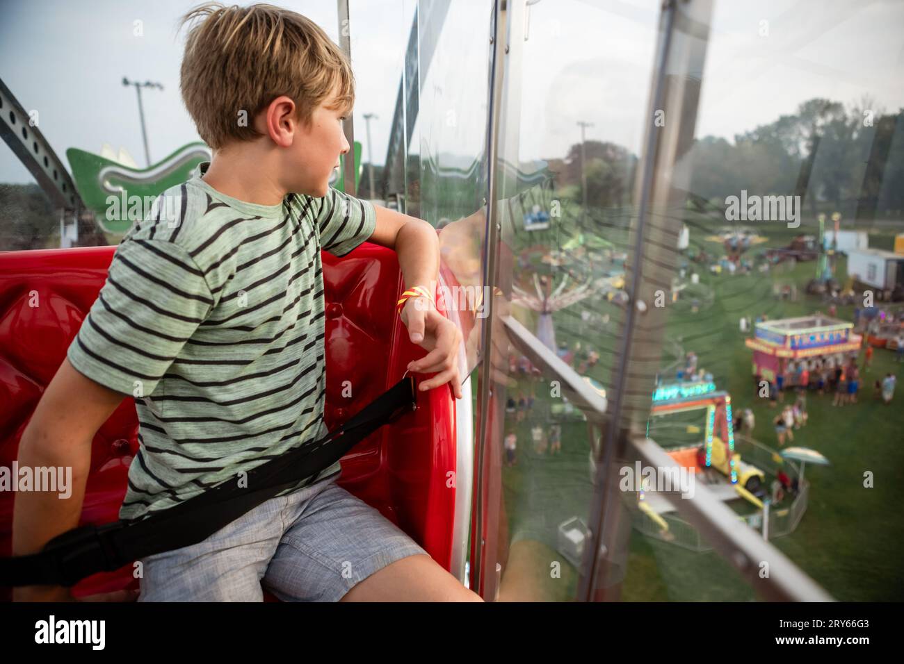 Child riding ferris wheel looking down at carnival Stock Photo - Alamy
