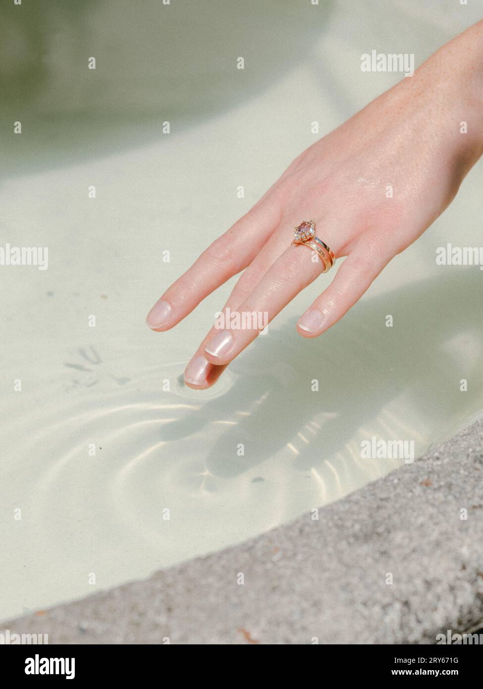 Delicate hand with wedding rings touches fountain of water Stock Photo ...